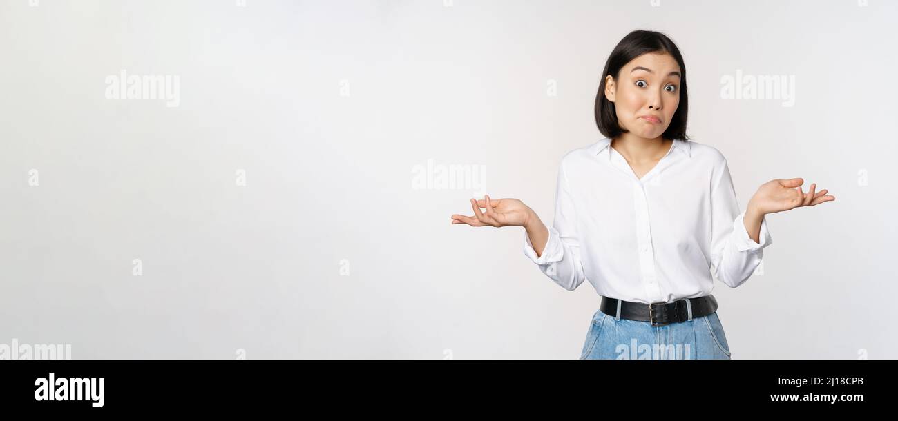 Image of confused asian office manager, office lady shrugging shoulders ...