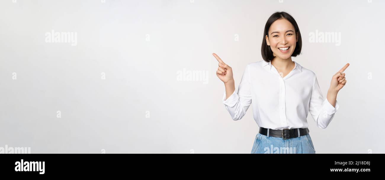 Image of beautiful asian woman pointing fingers left and right, making ...