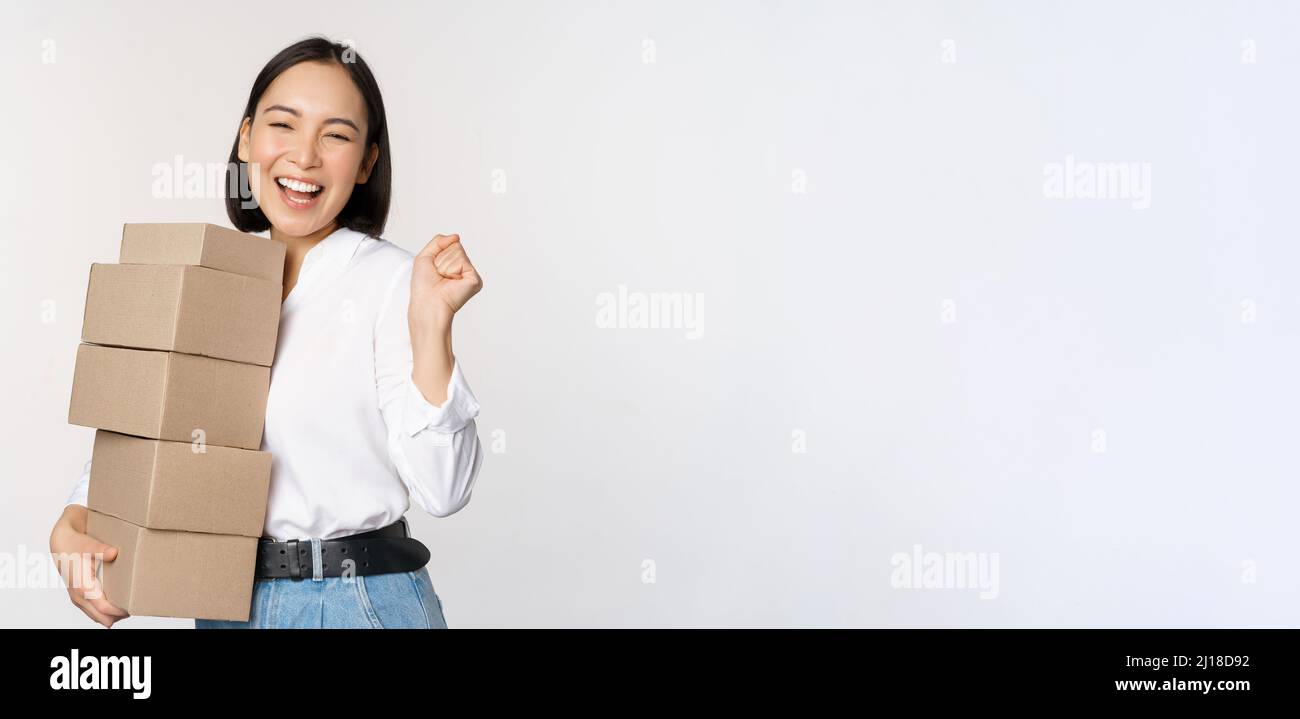 Enthusiastic korean girl shopper, holding boxes delivery and smiling ...