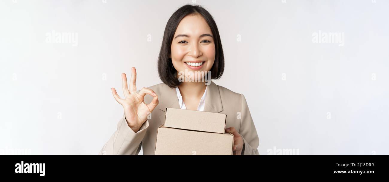 Smiling asian businesswoman, showing okay sign and boxes with delivery ...