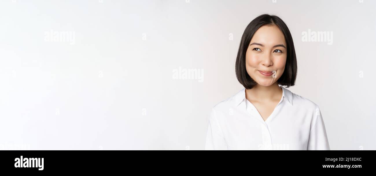 Image of smiling asian woman planning, thinking of smth, daydreaming ...