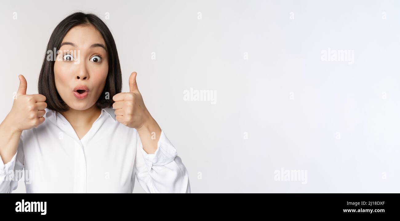 Cheerful asian woman face, showing thumbs up and smiling, pleased by ...