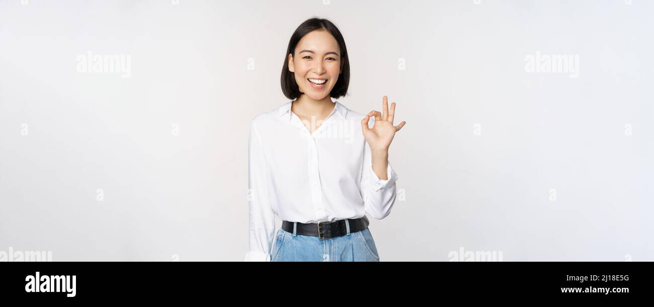 Very good. Smiling asian woman showing okay with satisfied face ...