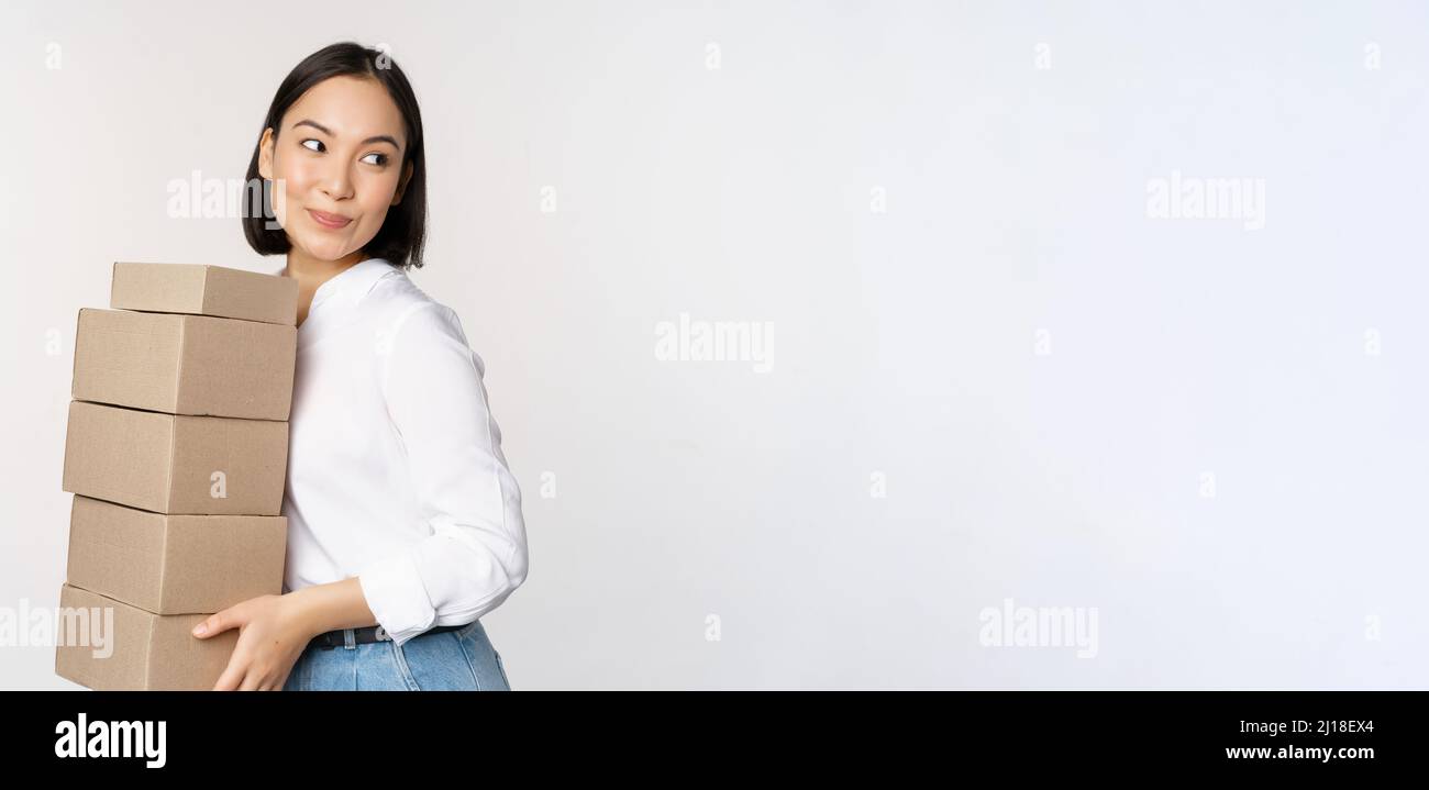 Portrait of young asian woman holding boxes, carry delivery goods. Korean female entrepreneur ...