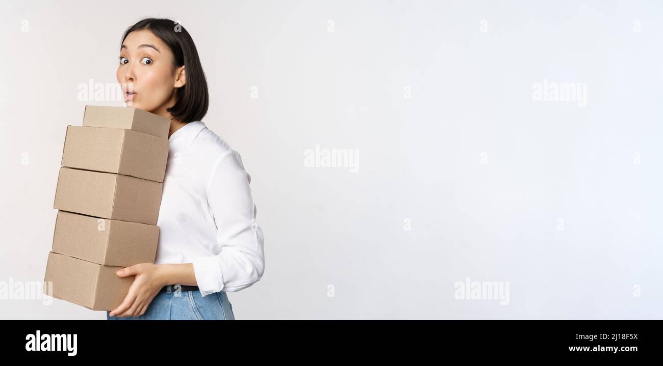 Portrait of young asian woman holding boxes, carry delivery goods ...