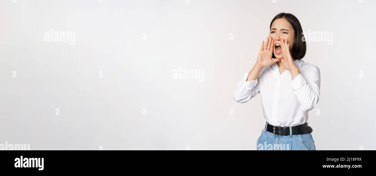 Image of young asian woman calling for someone, shouting loud and ...