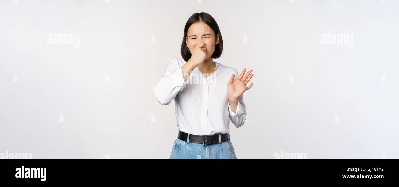 Disgusted asian girl close nose and showing rejection gesture ...