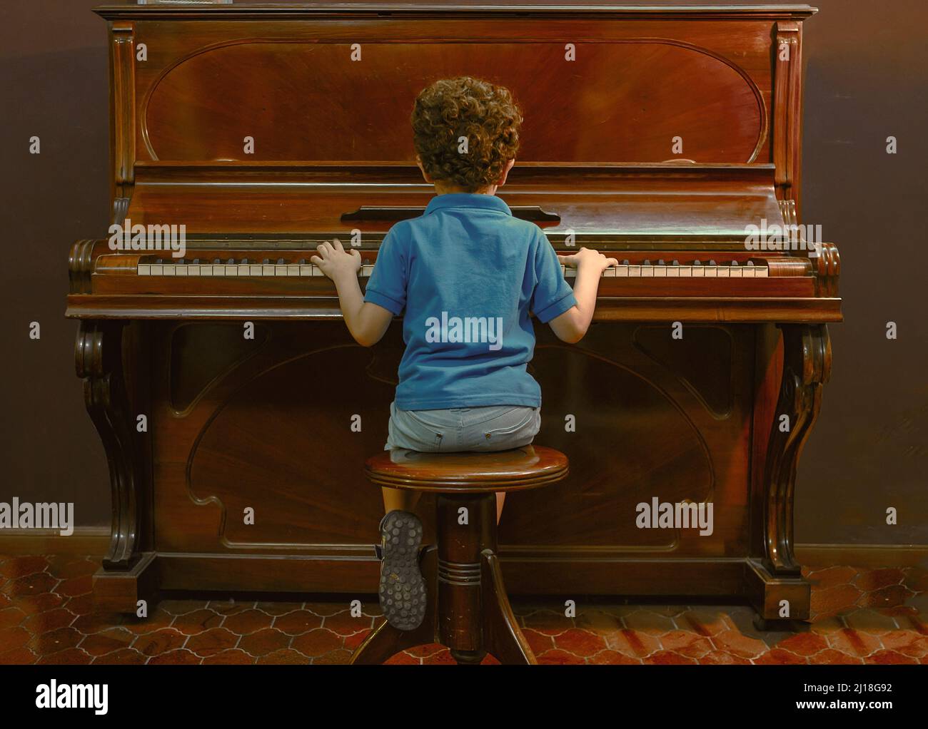 seen from behind as a child playing the piano Stock Photo - Alamy