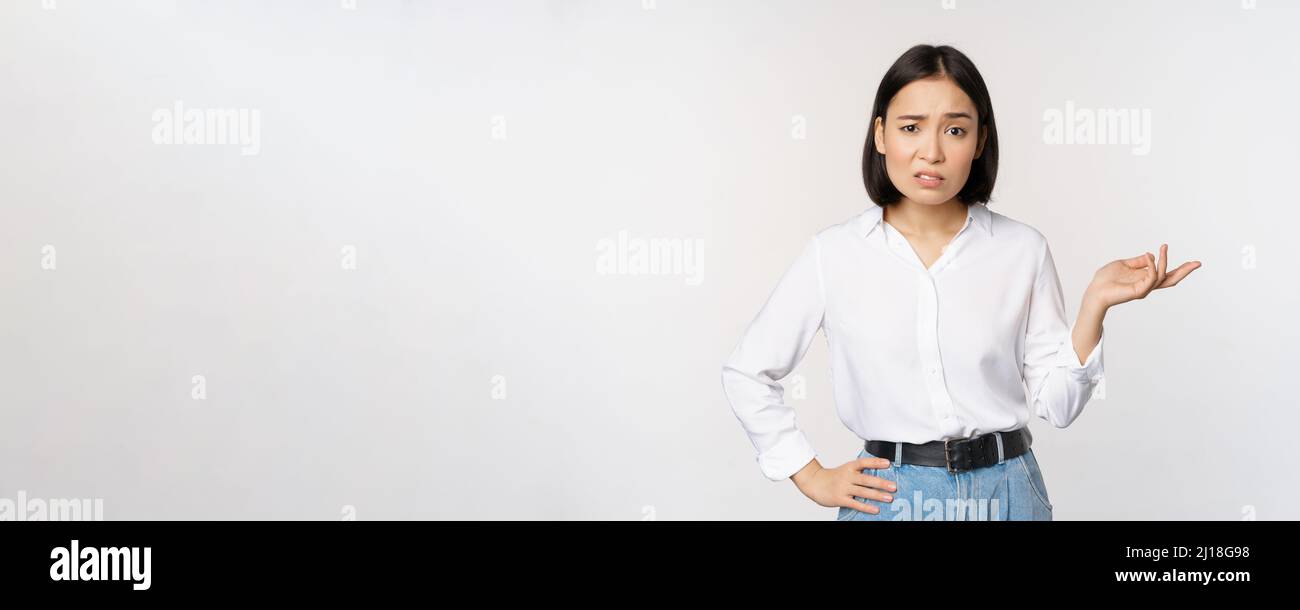Portrait of confused asian woman asking so what, whats your problem ...