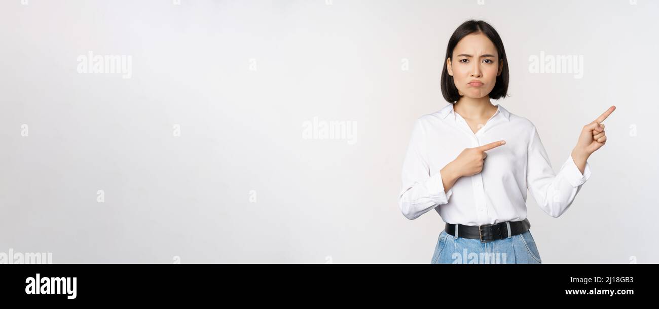 Sad and gloomy asian woman looking disappointed, complaining at banner ...