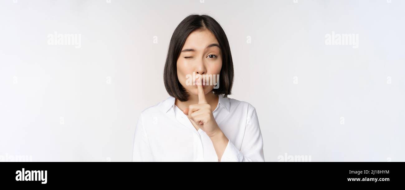 Close up portrait of young asian woman making hush, shhh shush sign ...