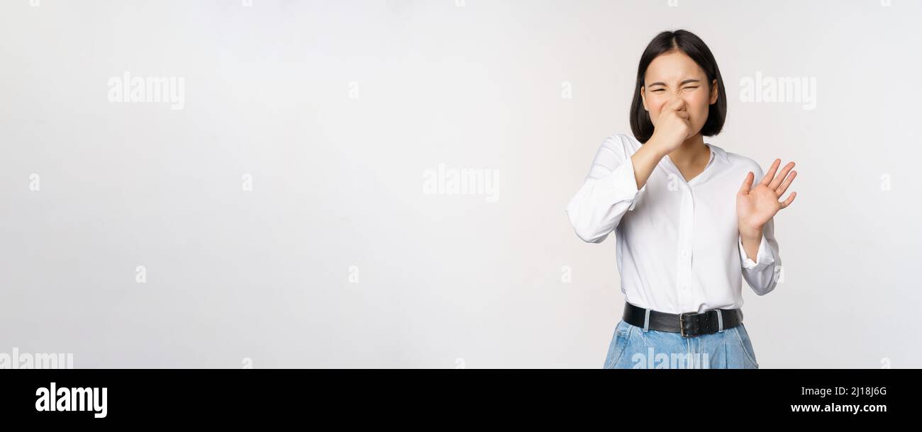 Disgusted asian girl close nose and showing rejection gesture ...