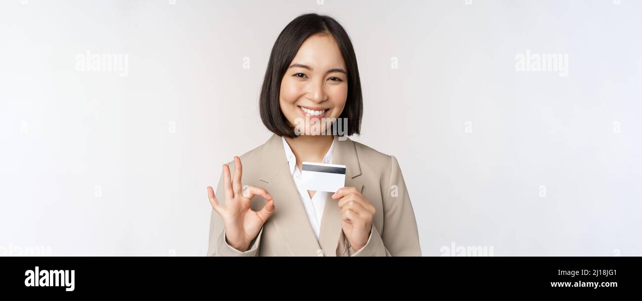 Smiling office clerk, asian corporate woman showing credit card and ...
