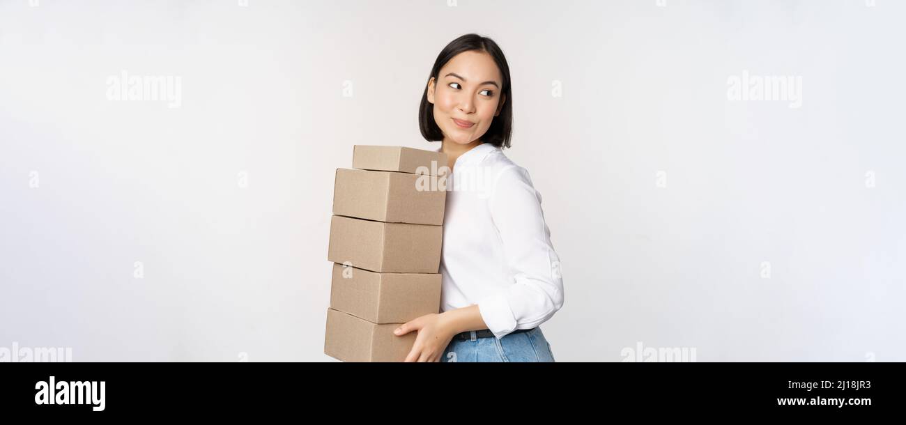 Portrait of young asian woman holding boxes, carry delivery goods. Korean female entrepreneur ...