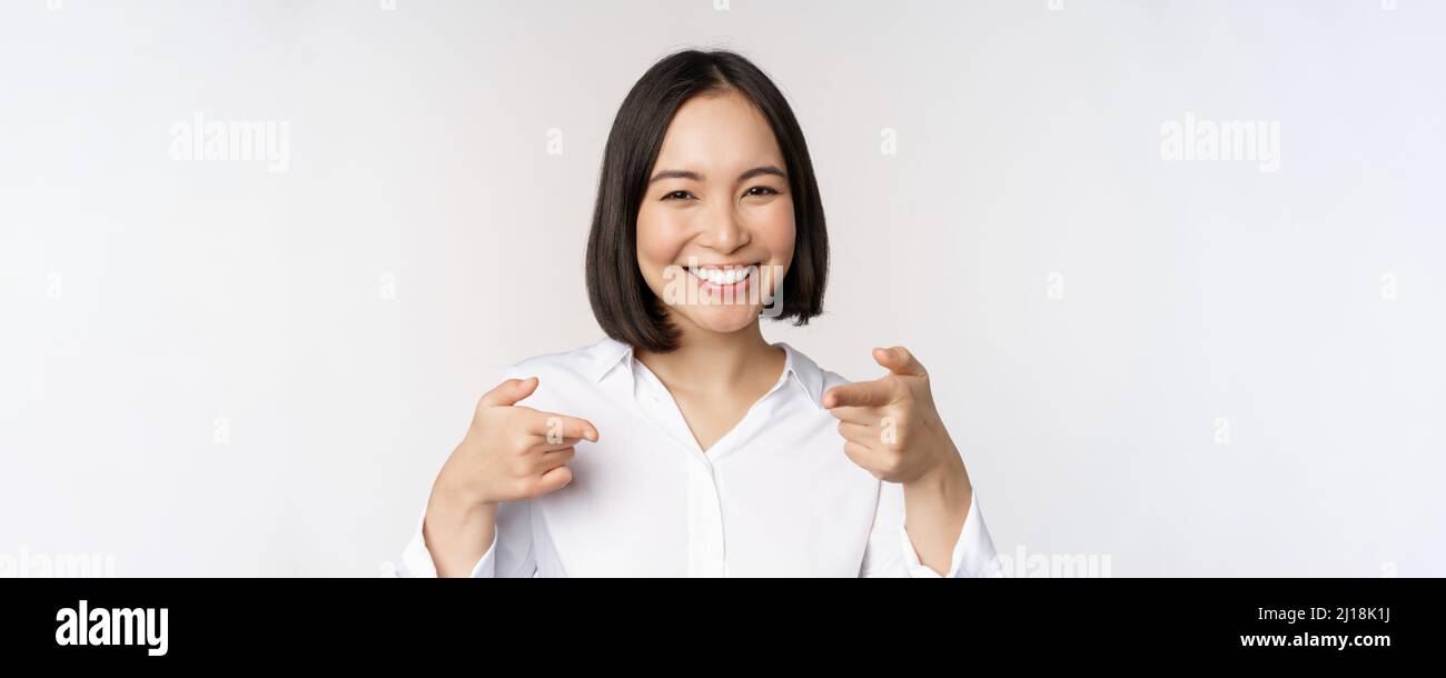 Close up of enthusiastic young woman smiling, pointing fingers at ...