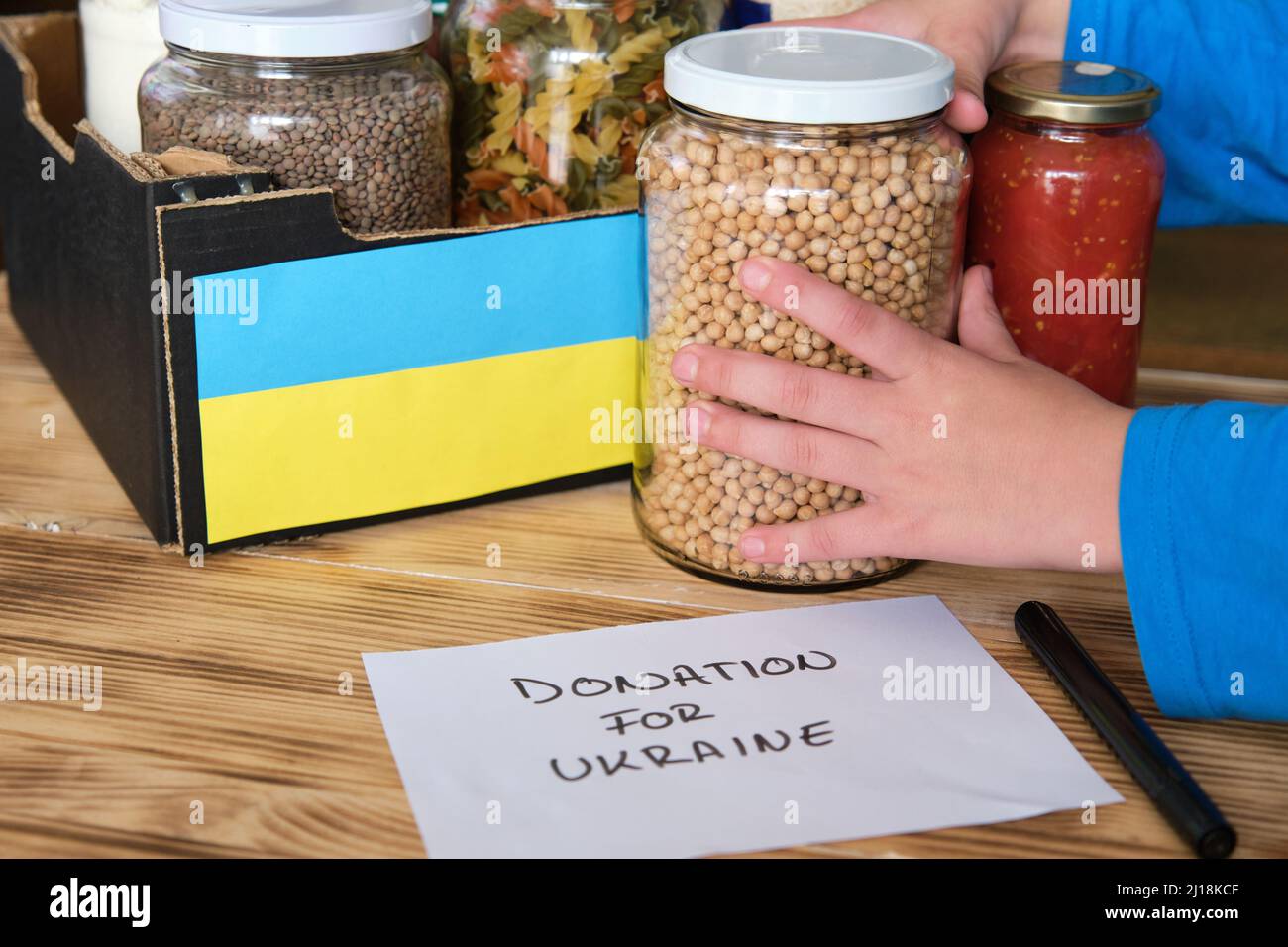A Person preparing a box with food to donate to the war in Ukraine ...