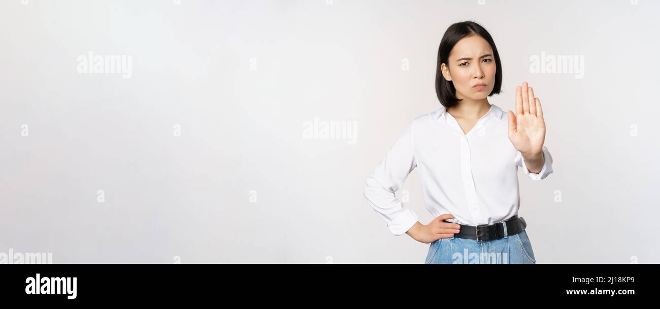 Portrait of young woman extending one hand, stop taboo sign, rejecting ...