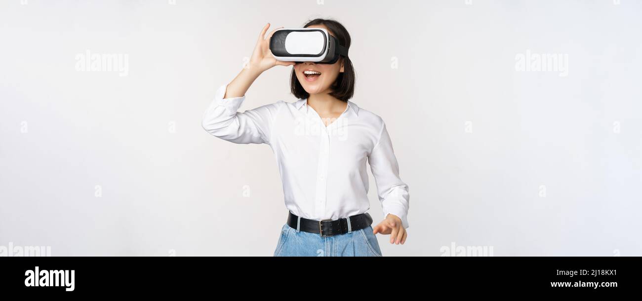 Excited young woman enter virtual reality in her glasses. Asian girl ...