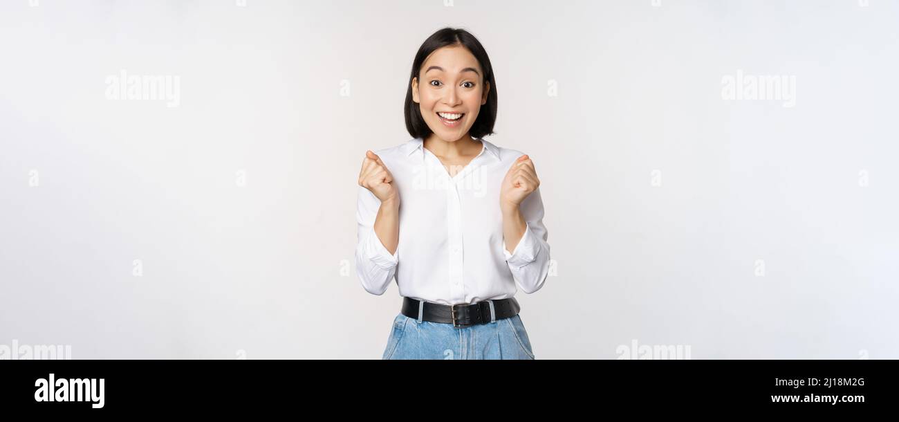 Enthusiastic asian woman rejoicing, say yes, looking happy and ...