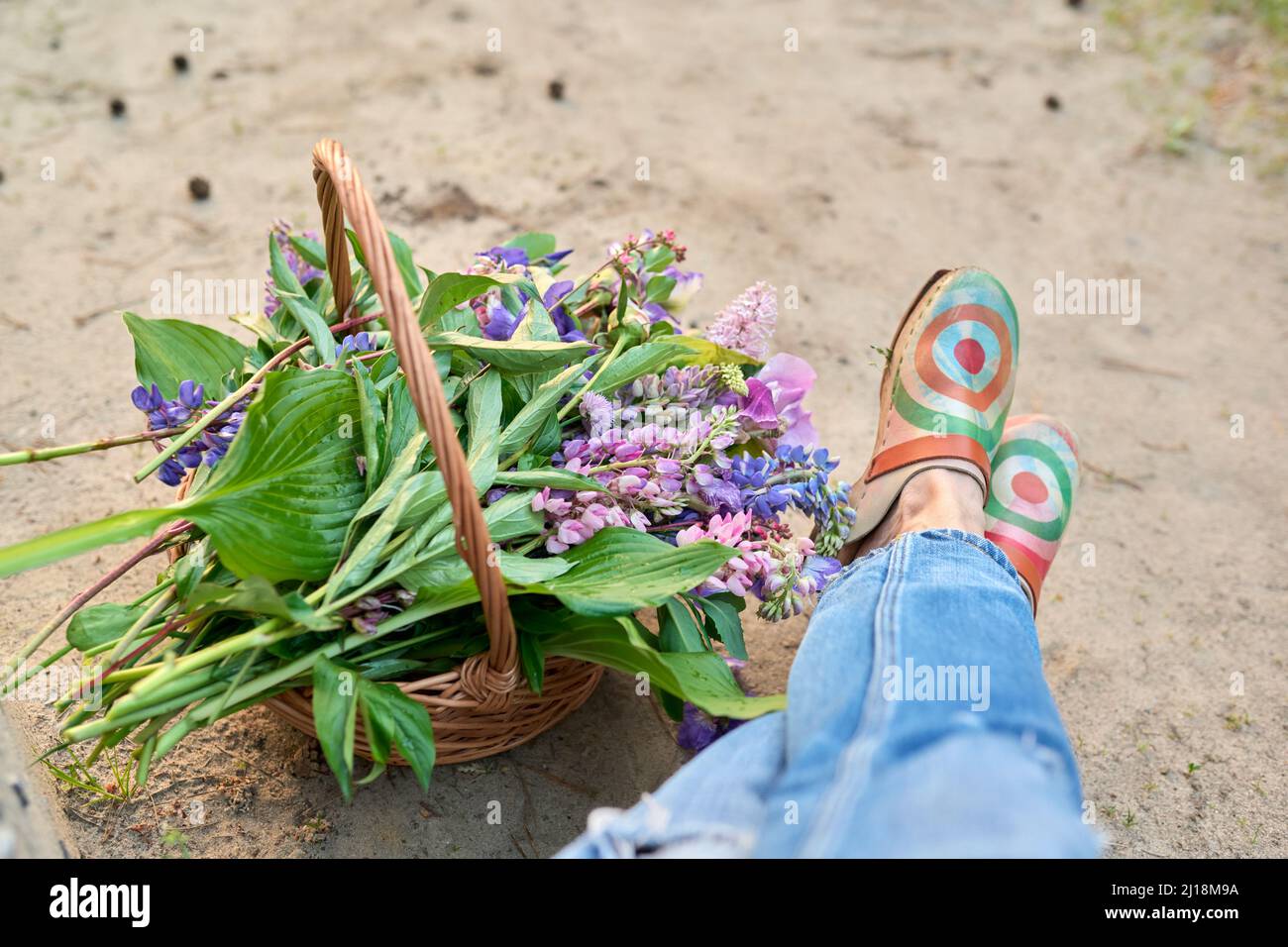 Spring fresh flowers in basket on ground with legs close up, top view ...