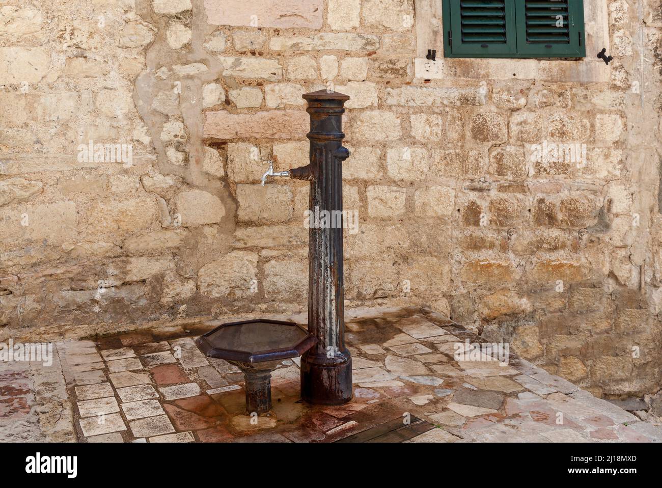 Old metal water column on the background of a stone wall. Architecture ...