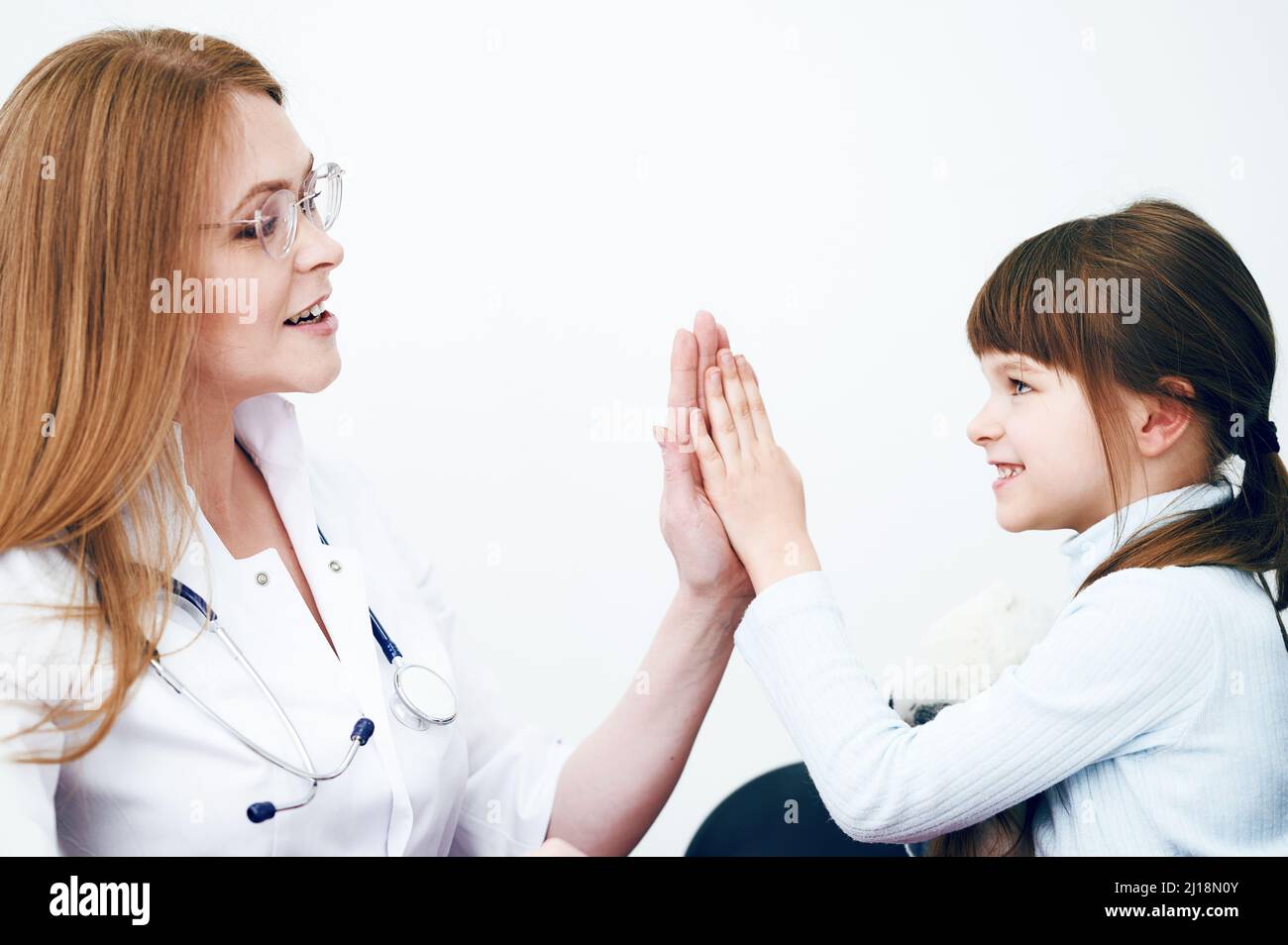Creative professional female pediatric giving her little patient a high ...