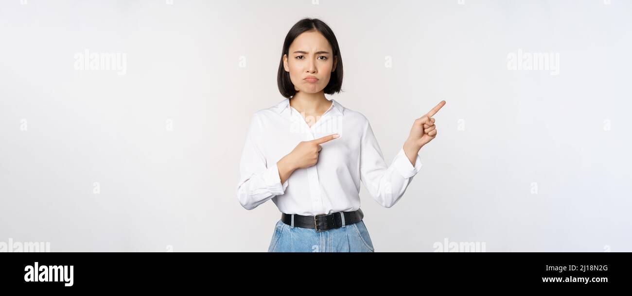 Sad and gloomy asian woman looking disappointed, complaining at banner ...