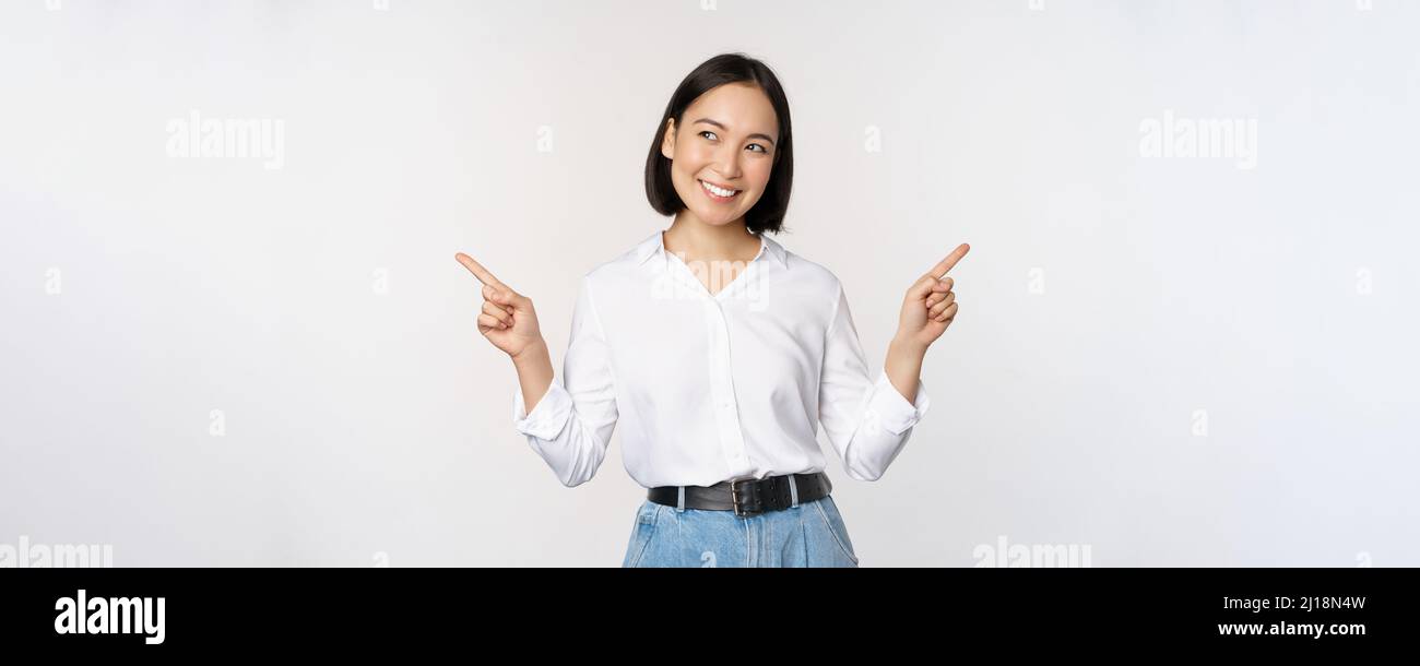 Image of beautiful asian woman pointing fingers left and right, making ...
