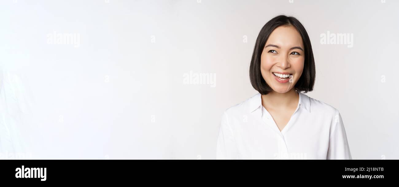 Image of smiling asian woman planning, thinking of smth, daydreaming ...