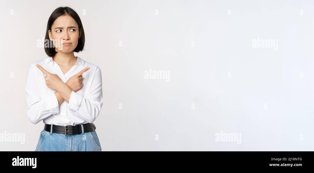 Indecisive asian woman pointing fingers sideways, pointing fingers and ...