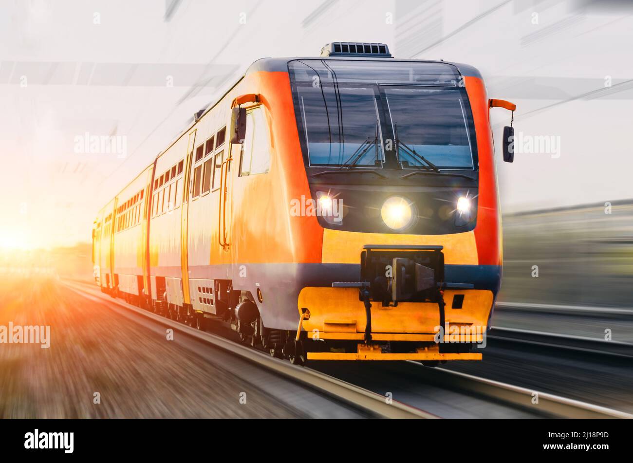 Red orange passenger train with headlights on rushing through the ...