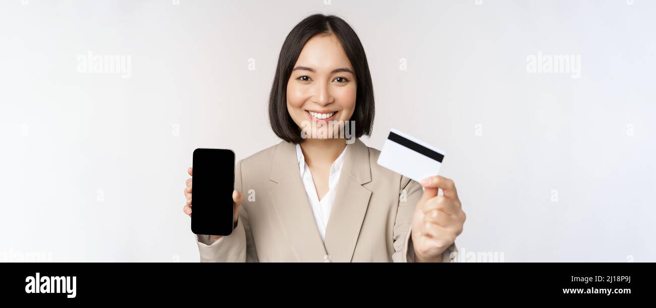 Smiling corporate woman in suit, showing mobile phone screen and app on ...