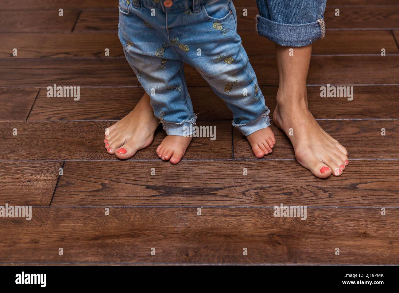 Mom and daughter barefoot in jeans on a warm wooden floor Stock Photo ...