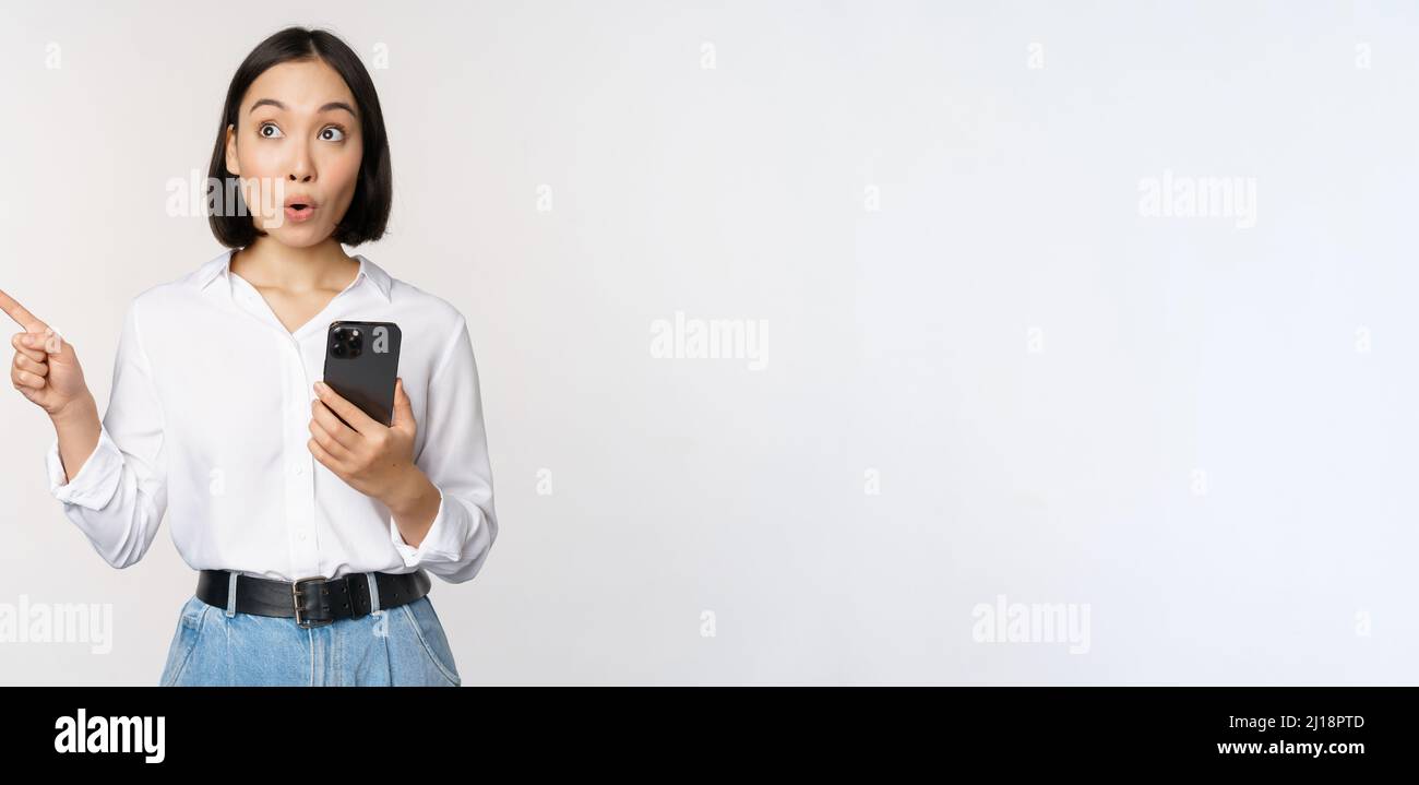 Excited asian girl shopping on mobile app, holding phone and pointing ...