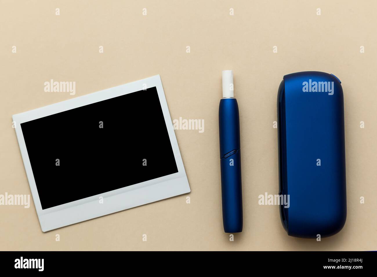 Electronic blue IQOS cigarette, with a photo frame on a beige ...