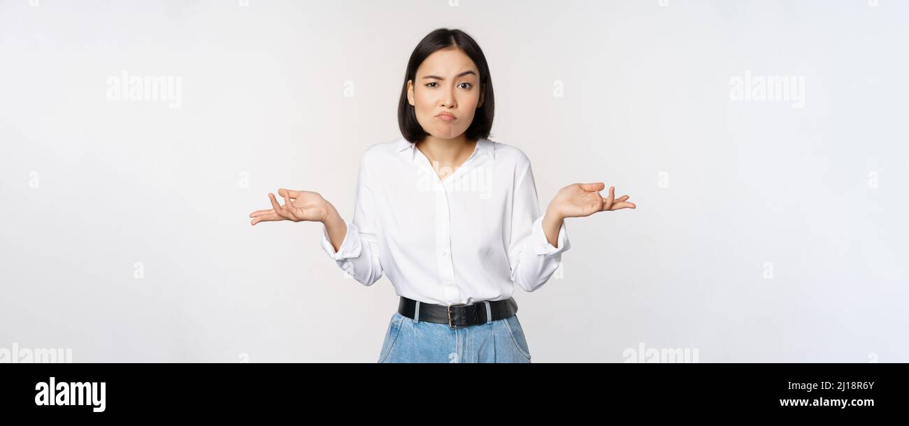 Image of confused asian office manager, office lady shrugging shoulders ...
