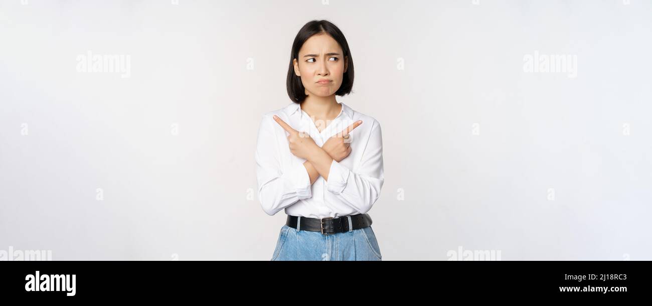 Indecisive asian woman pointing fingers sideways, pointing fingers and ...