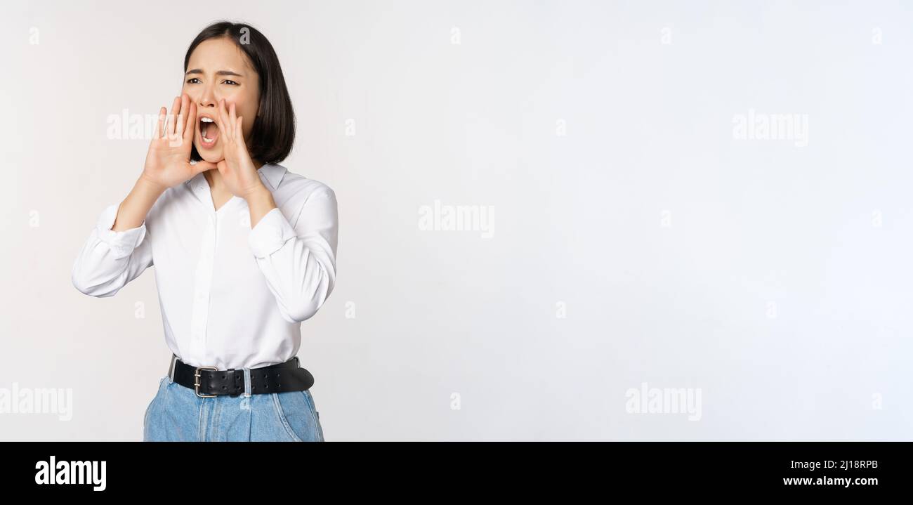 Image of young asian woman calling for someone, shouting loud and ...