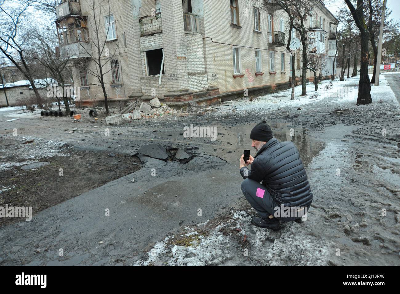 SIEVIERODONETSK, UKRAINE - MARCH 4, 2022 - A man captures the crater on ...