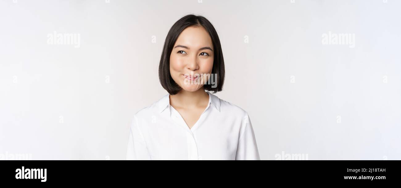 Image of smiling asian woman planning, thinking of smth, daydreaming ...