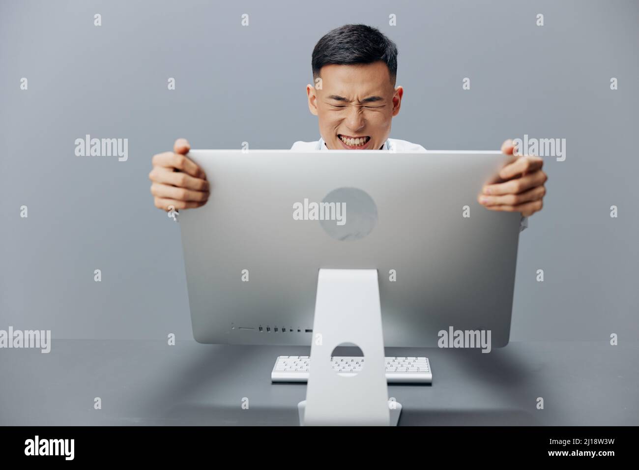 Asian man working in front of computer sitting at a table in the office ...