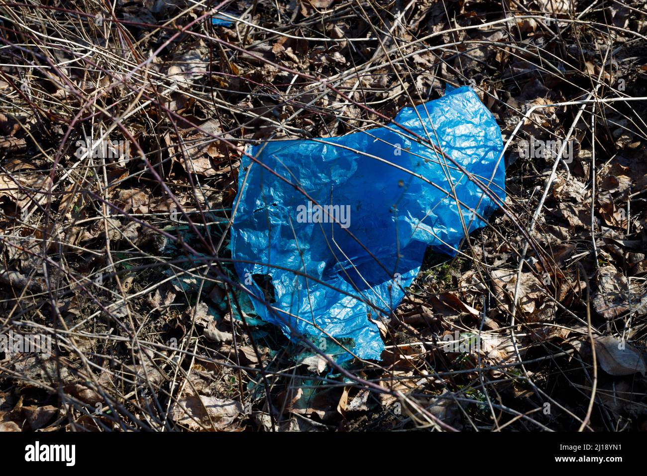 Old blue plastic package on the ground, littering and a plastic problem ...