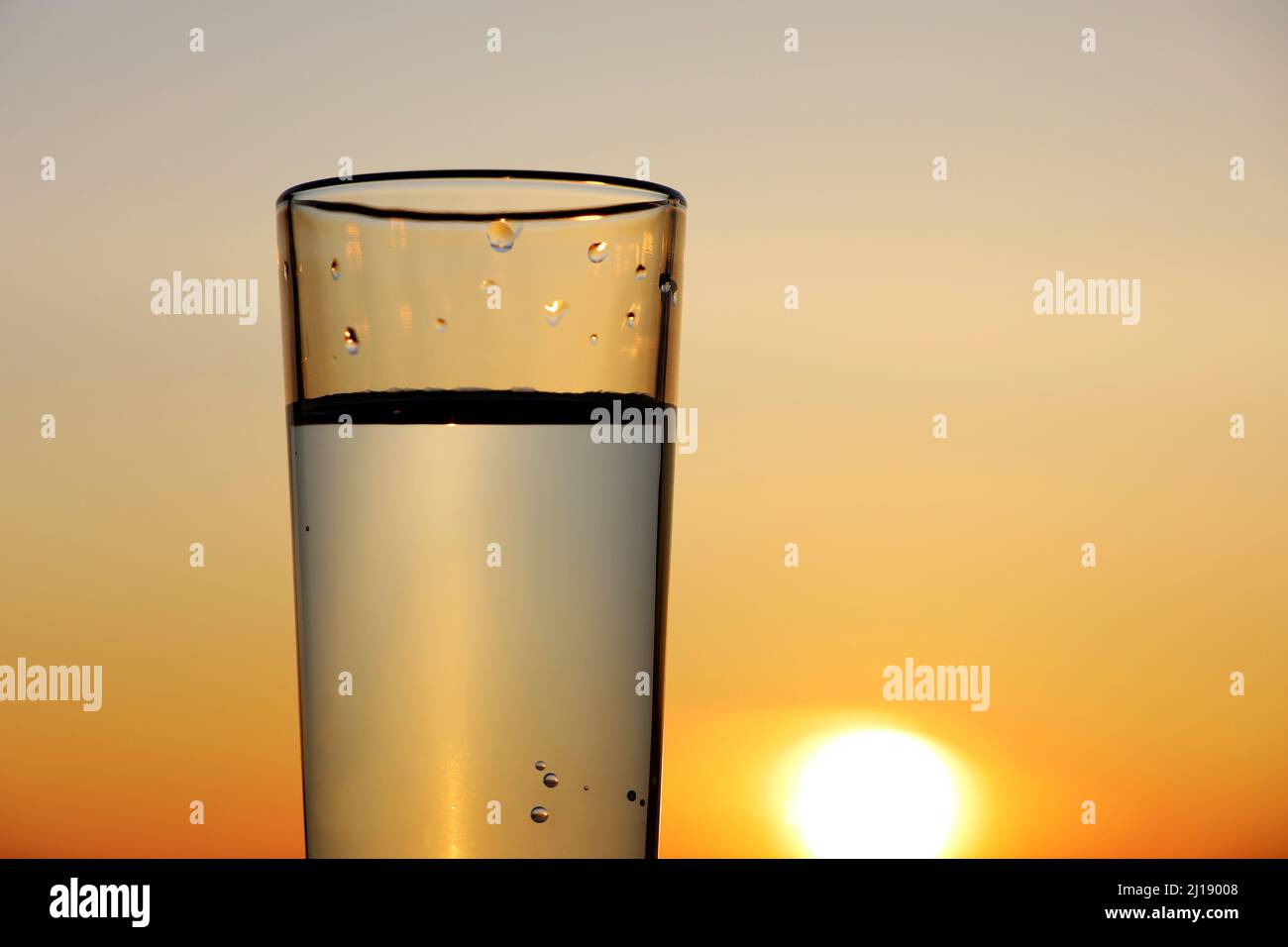 Clean water in drinking glass on sunset sky background. Water ...