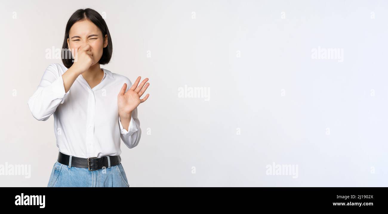 Disgusted asian girl close nose and showing rejection gesture ...