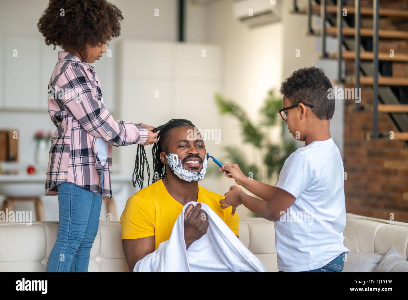 Boy shaving dad and girl weaving dreadlocks Stock Photo - Alamy