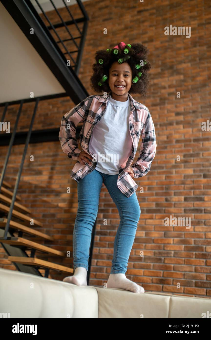 Girl standing on couch looking at camera Stock Photo - Alamy