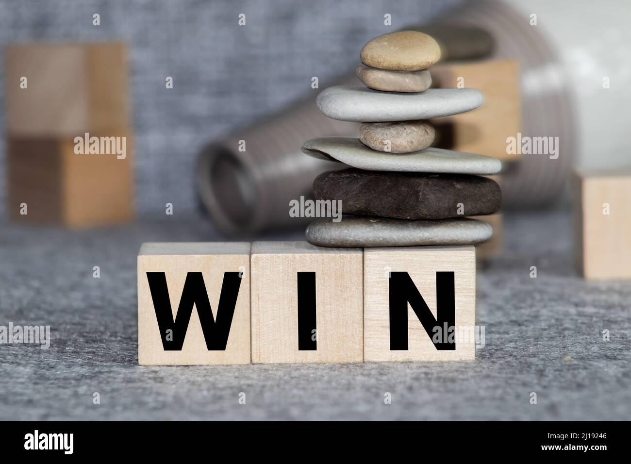 Three wooden cubes with word WIN, on white table, more in background ...