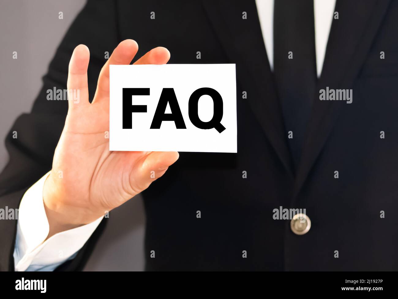 Businessman putting a card with text FAQ Stock Photo - Alamy