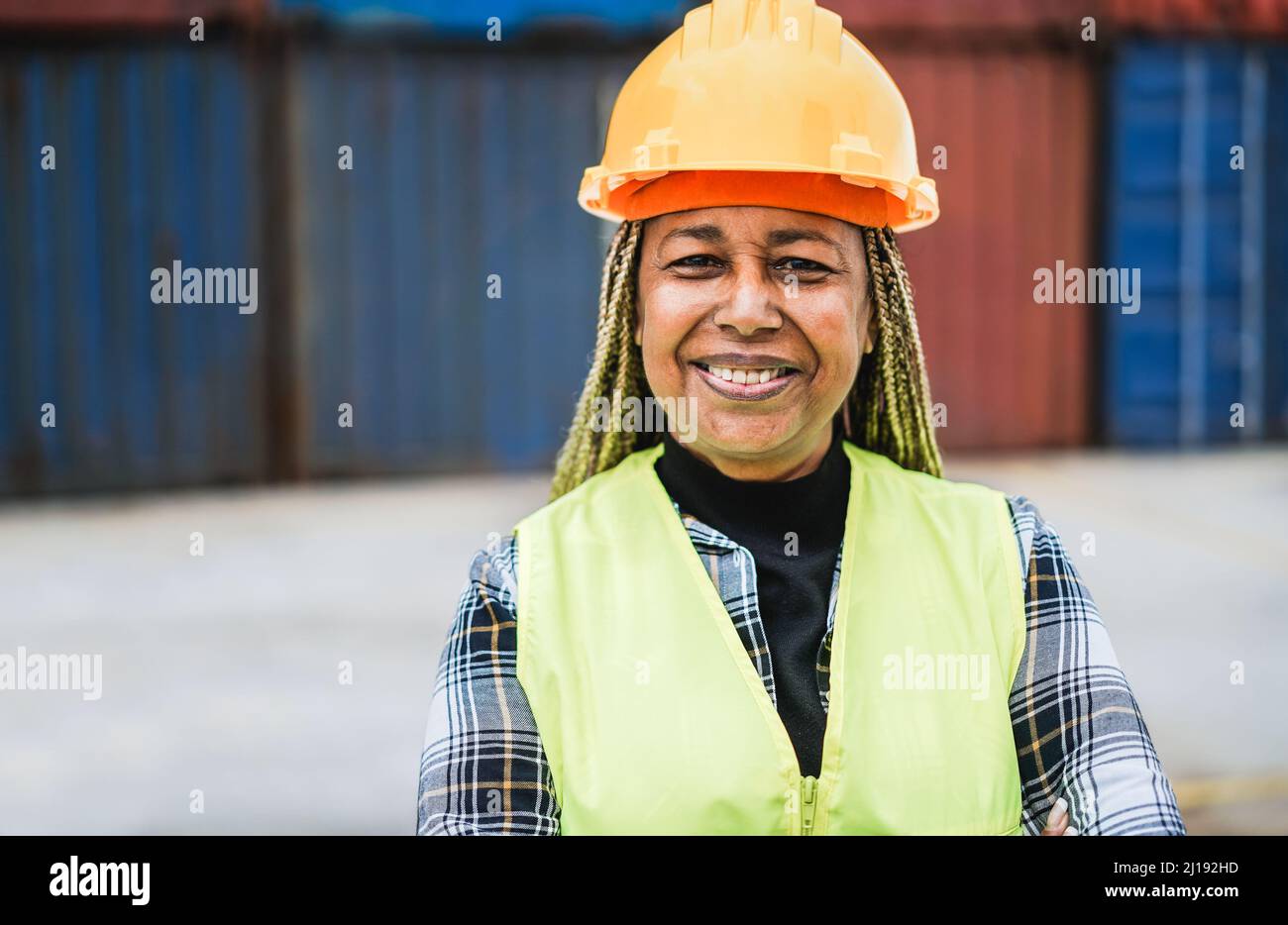 Worker African senior woman smiling on camera with industrial port on ...