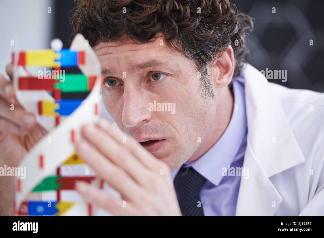 Fascinated by DNA. A cropped shot of a scientist examining a DNA model ...